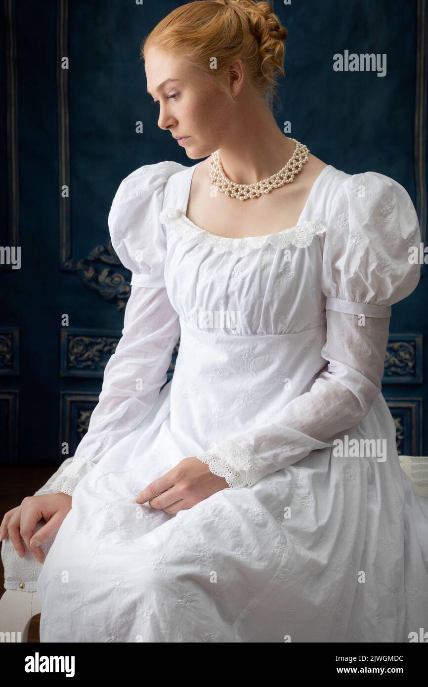 A Regency woman wearing a white embroidered muslin gown with a pearl ...