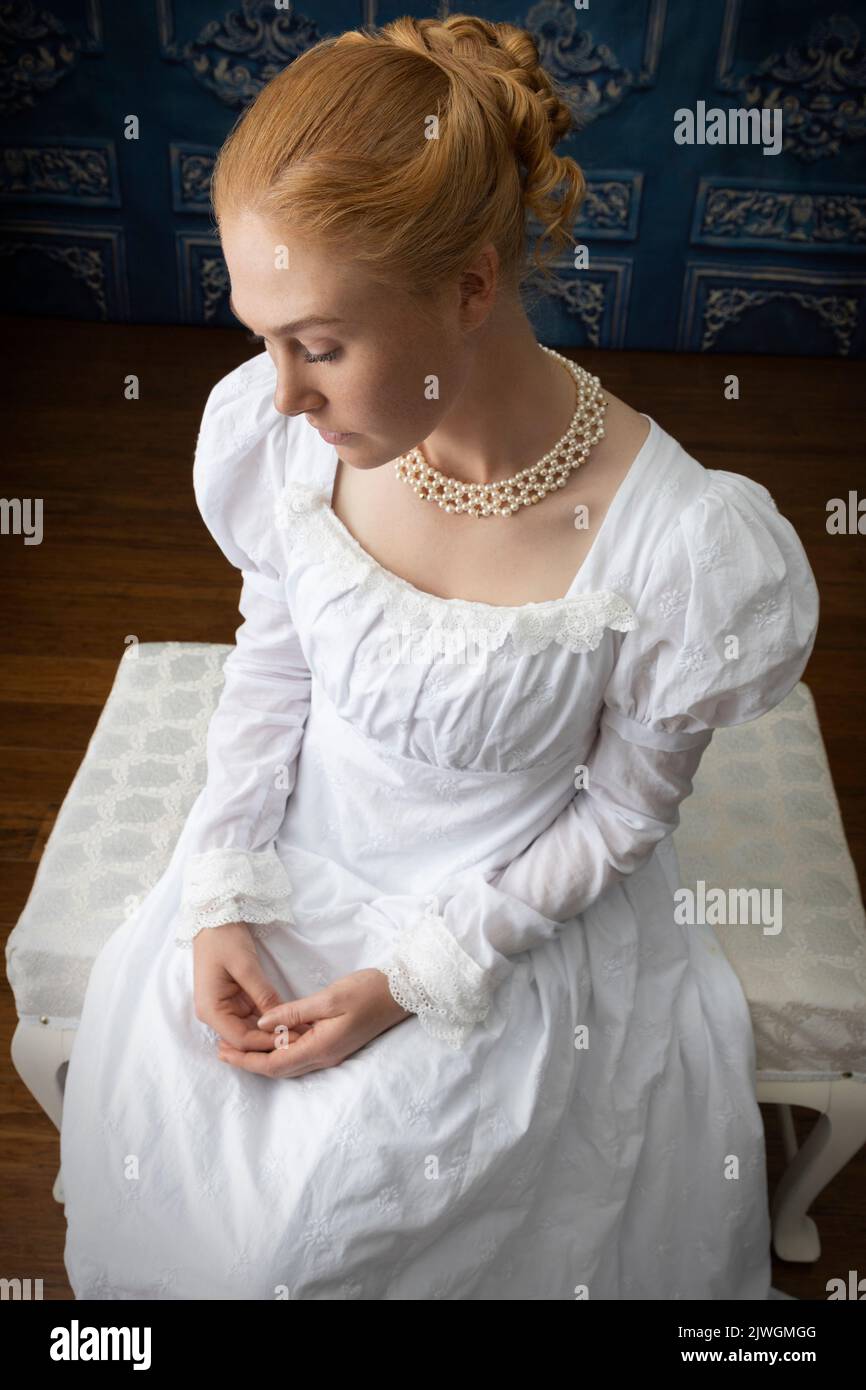 A Regency woman wearing a white embroidered muslin gown with a pearl ...