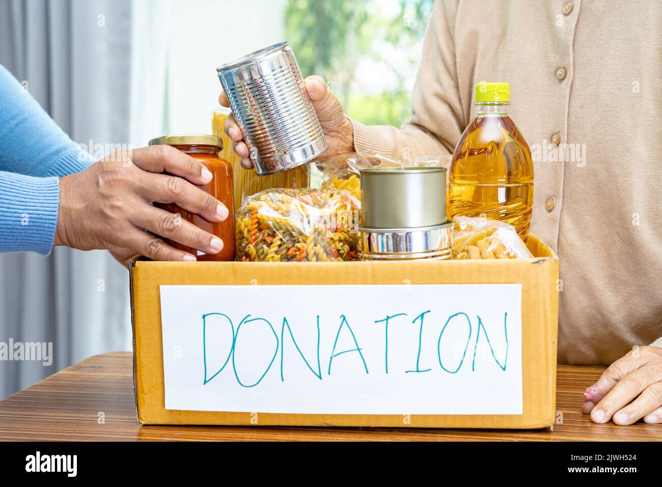 Volunteers putting various dry food in donation box for help people ...