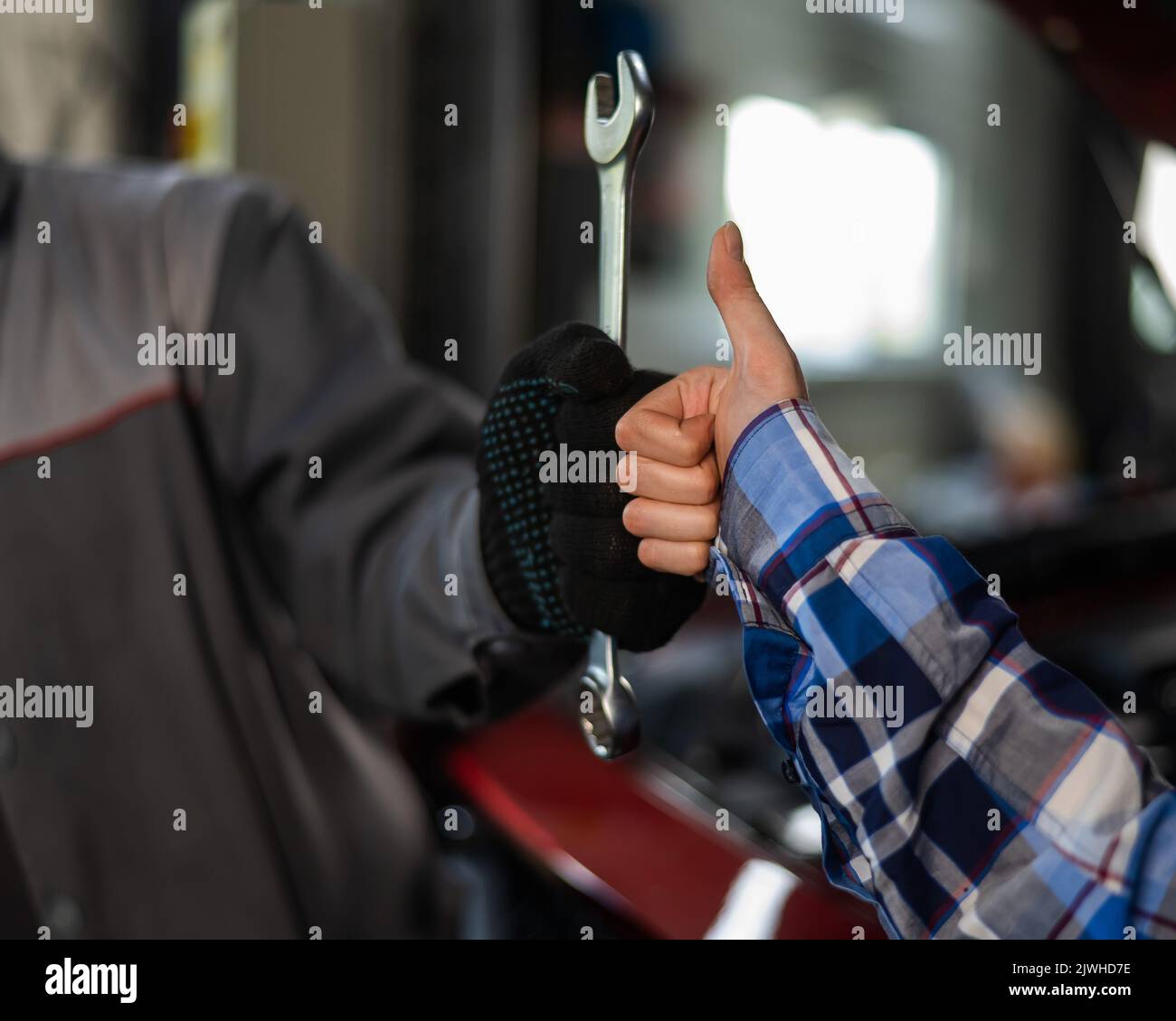 Close-up of woman's hand thumb up and mechanic's hand with tool ...
