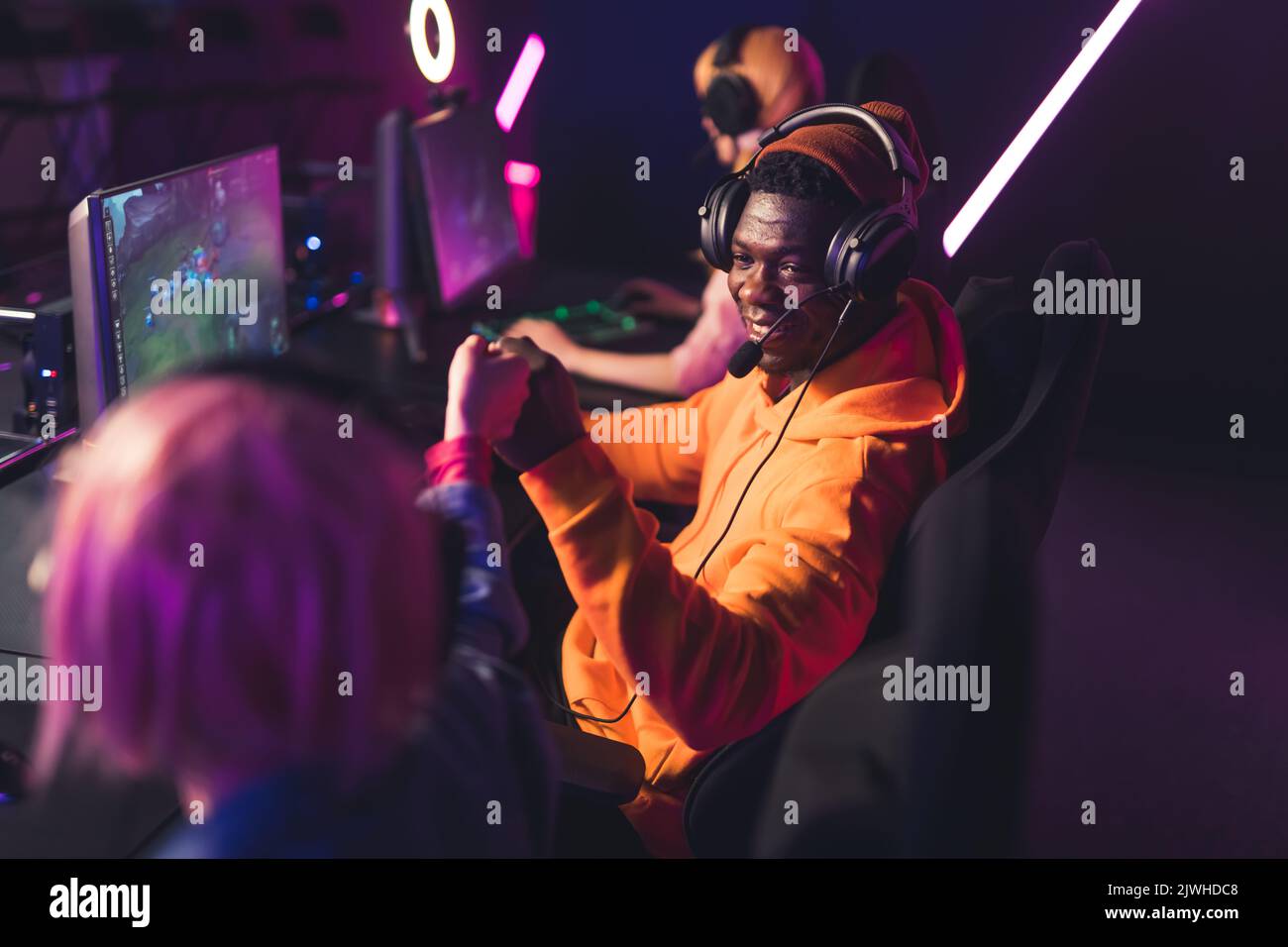 Three teenagers wearing colorful clothes playing online game using ...