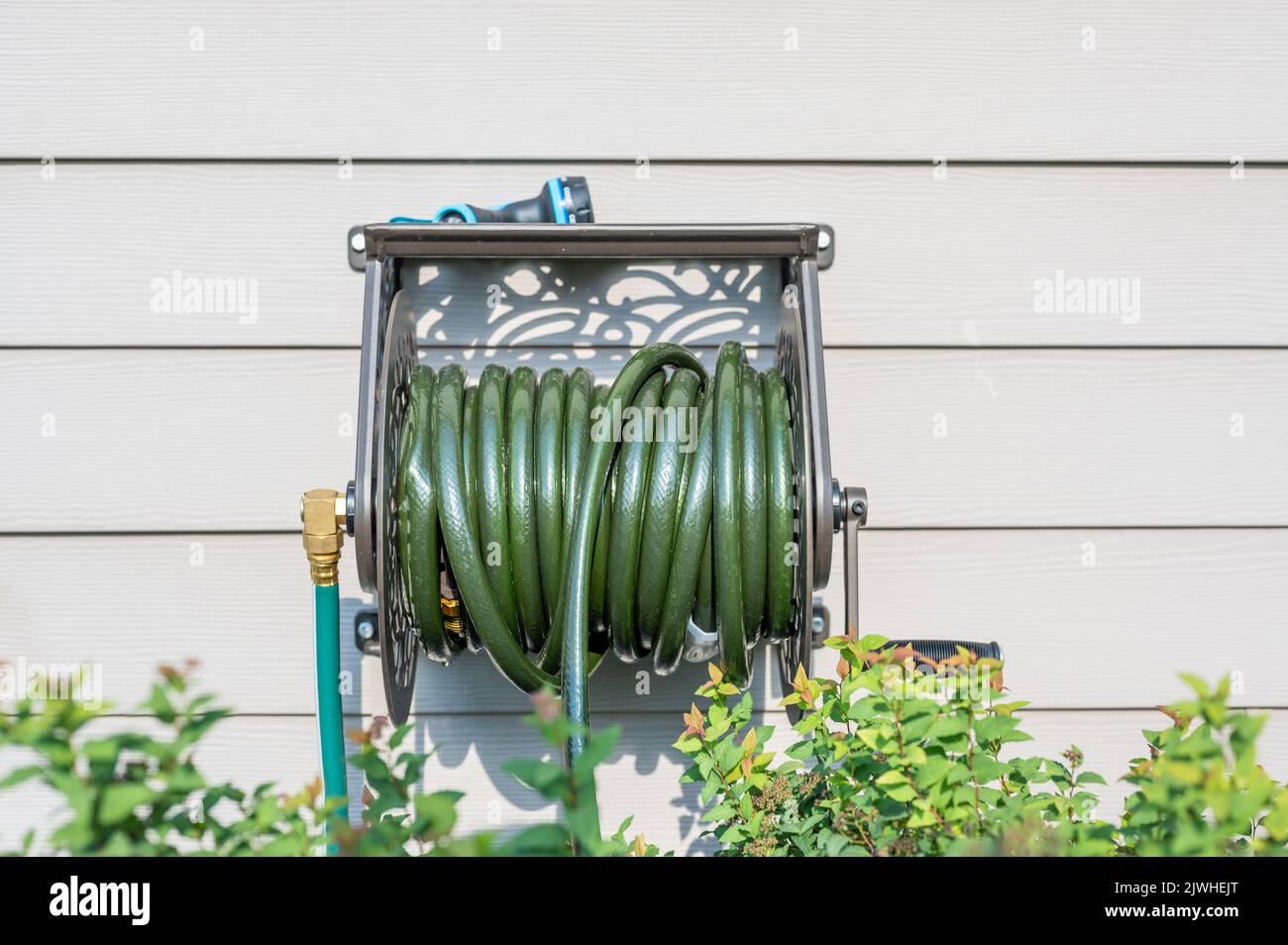 Decorative metal hose storage wheel mounted on the exterior of a ...