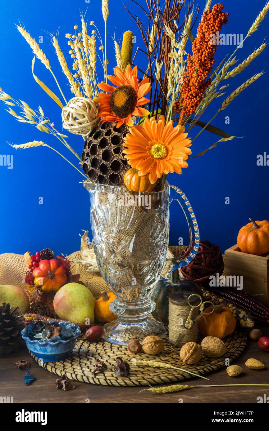 Autumn themed still life flower arrangement against a bright blue ...