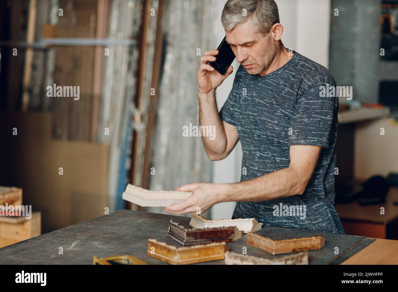 Framing Workshop. Man carpenter call mobile cell phone client baguette ...