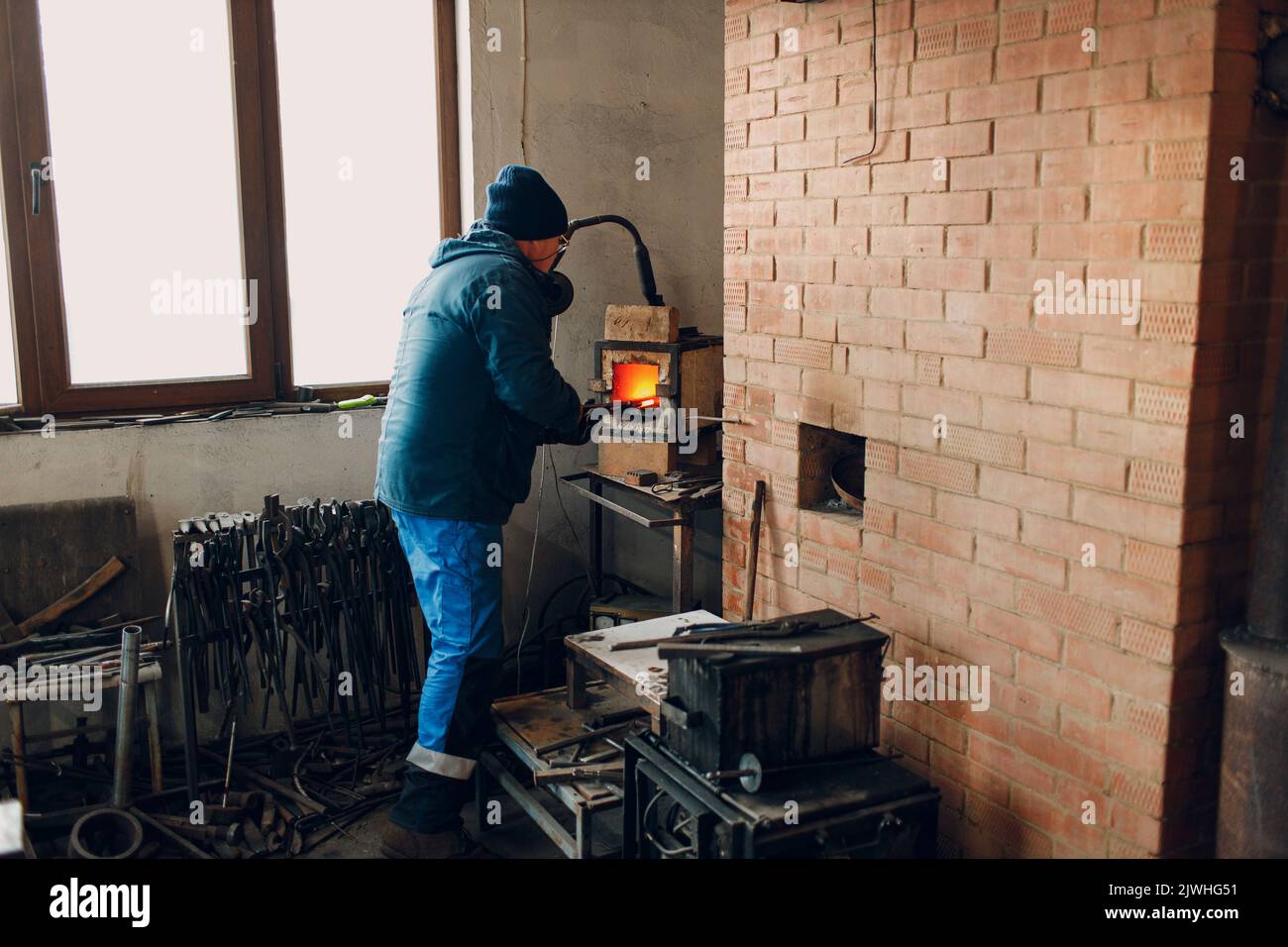 Blacksmith forge oven with hot flame. Smith put in and heating iron ...