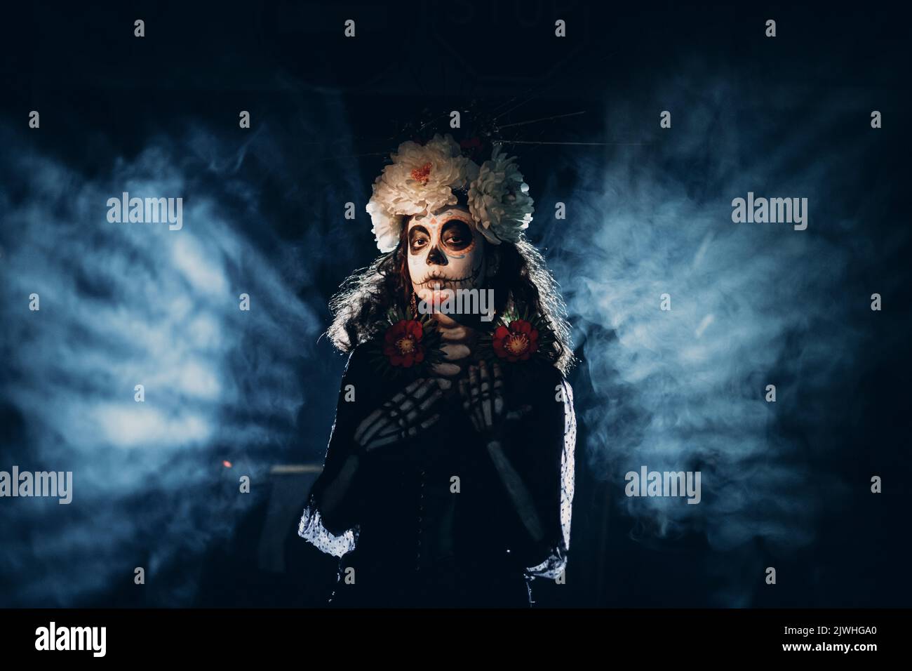 Woman with mexican skull halloween makeup in dark with backlight rays ...