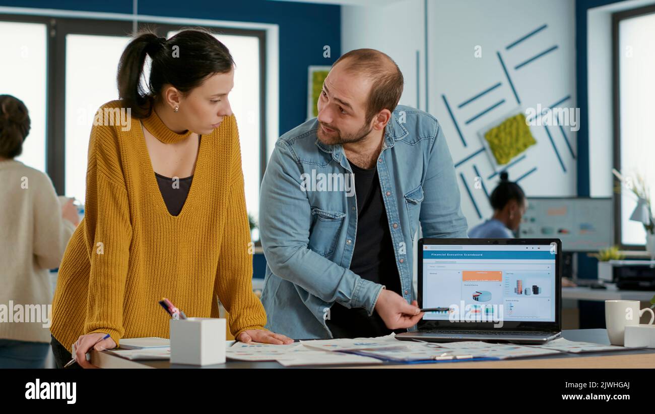 Colleagues in office comparing papers with sales charts with market ...