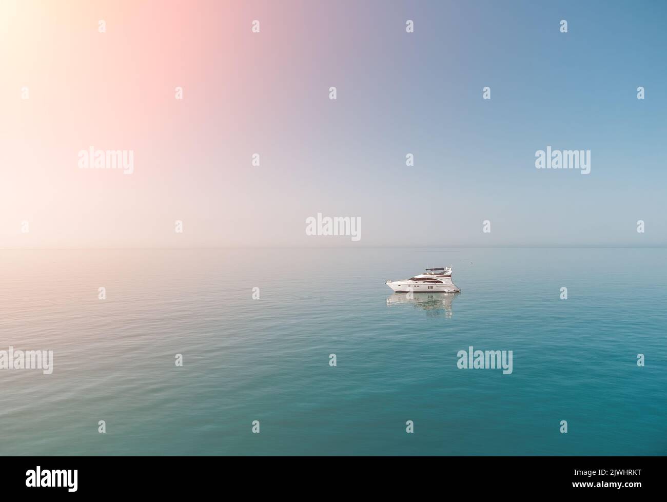 Aerial yacht on calm sea. Luxury cruise trip. View from above of white boat on deep blue water ...