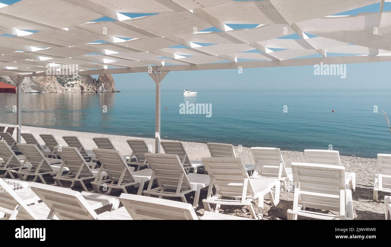 Empty sun loungers under a canopy on the beach. The beach area is empty ...