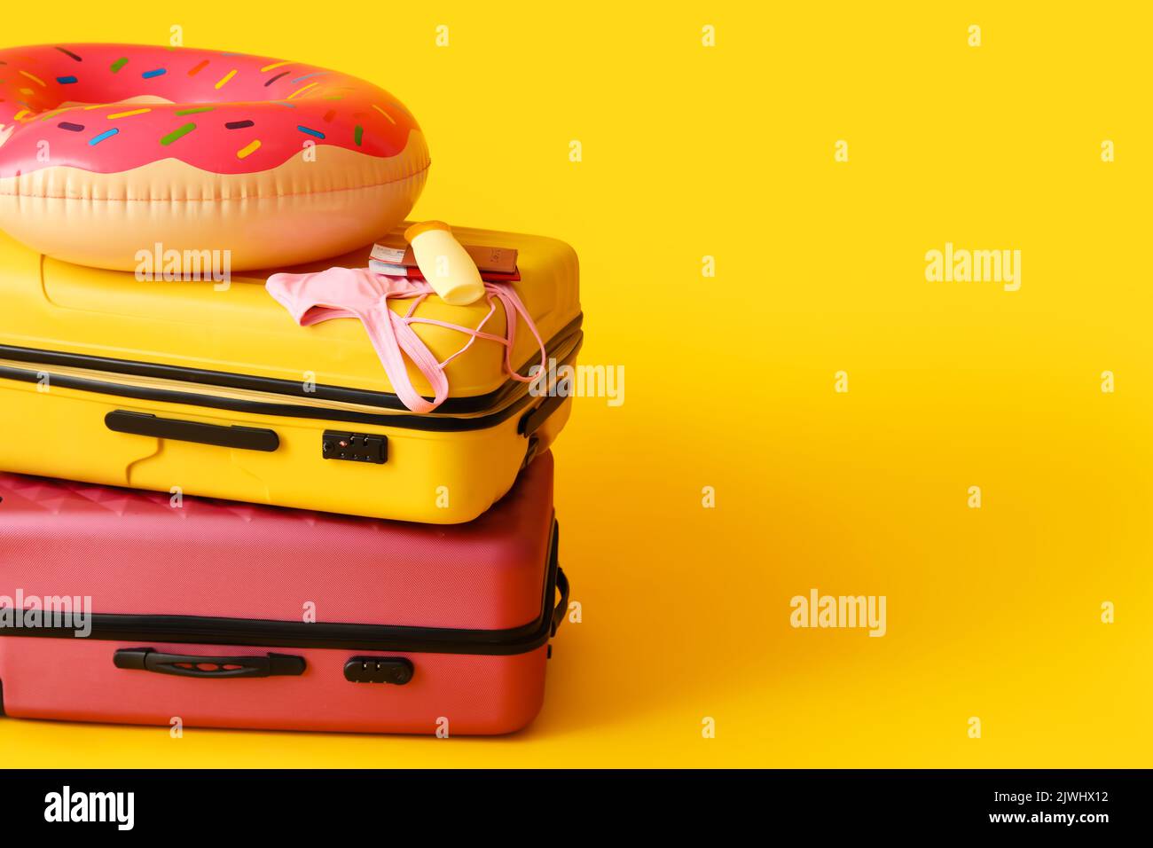 Suitcases with bottle of sunscreen, bikini bra, passports, tickets and ...