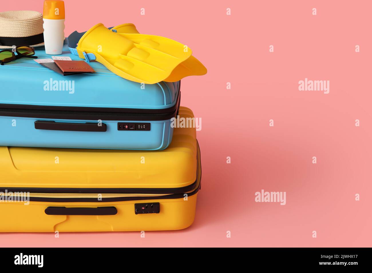 Suitcases, flippers, bottle of sunscreen and documents on pink ...