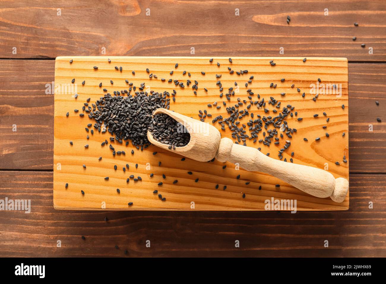 Board with scoop of black sesame seeds on wooden background Stock Photo ...