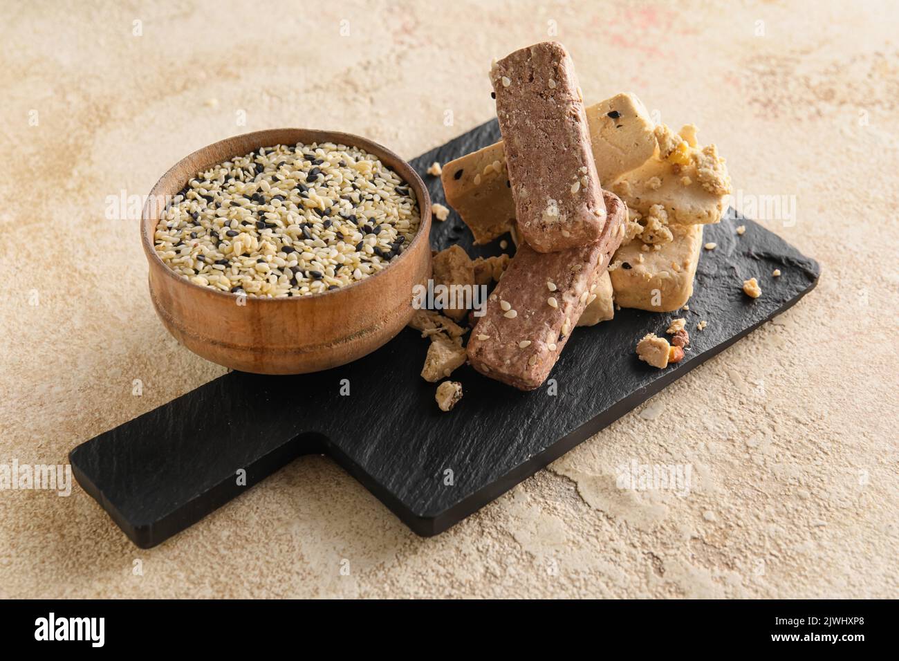 Board with bowl of sesame seeds and halva on light background Stock ...