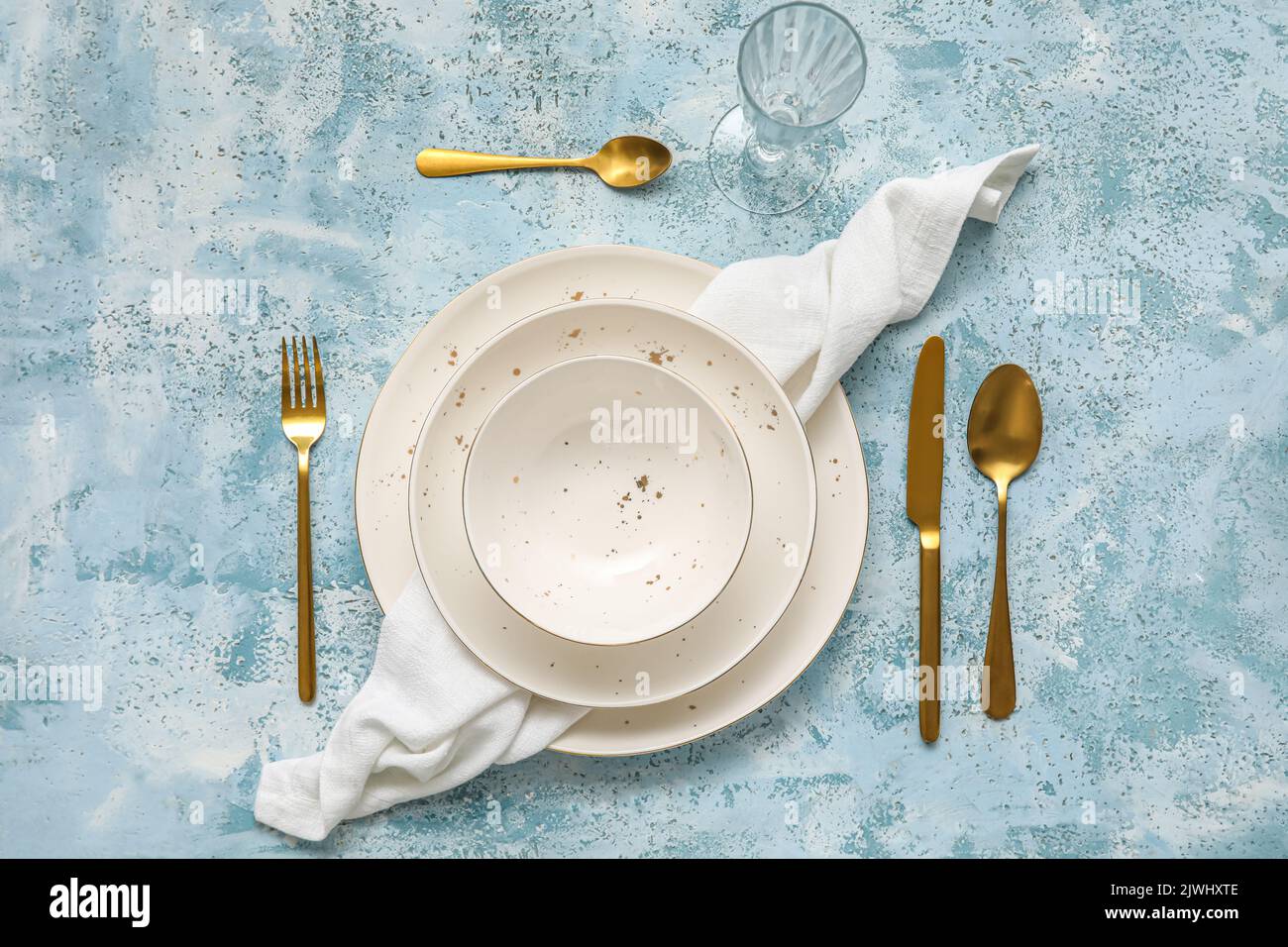Simple table setting with plates, cutlery and glass on blue background ...