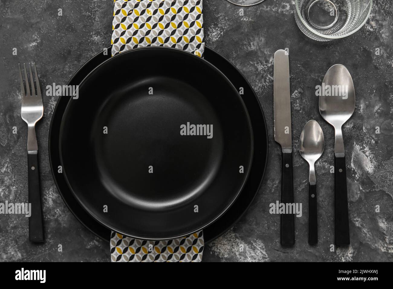 Elegant table setting with plates, cutlery and napkin on dark ...