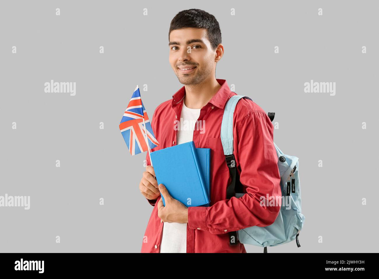 Young man with UK flag, books and backpack on grey background Stock ...