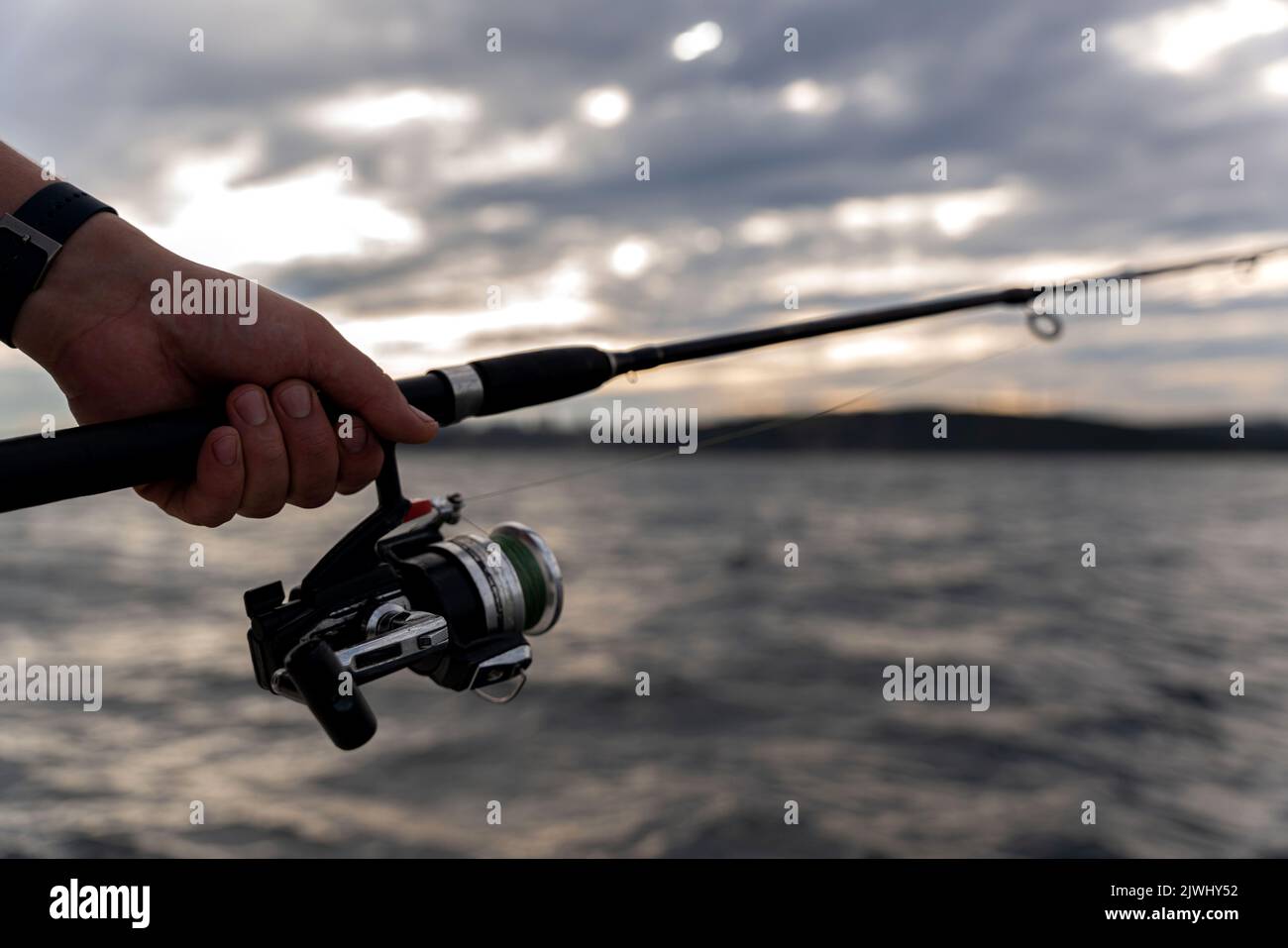 Fishing rod wheel closeup, man fishing with a beautiful sunrise behind ...