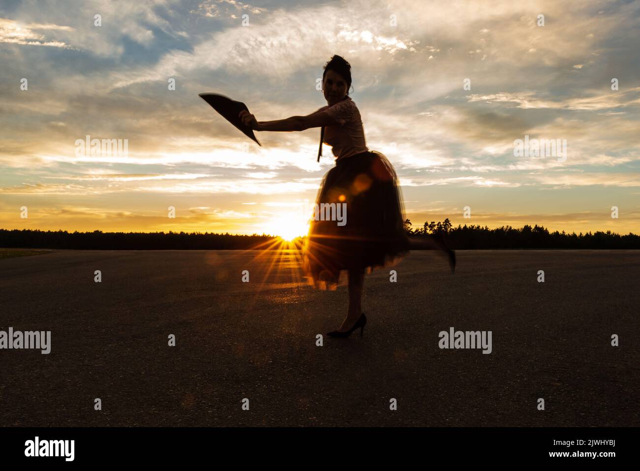 Dancing sunset fairy in rays of setting sun with hat in her hands ...