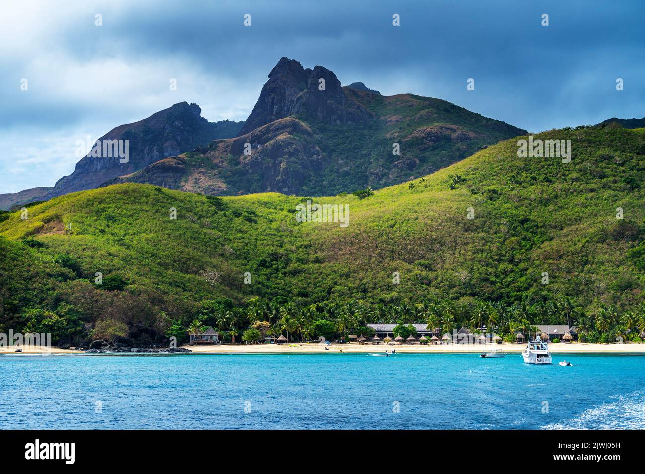 Tourist Resort on beach beneath rugged volcanic peaks of Waya Island ...