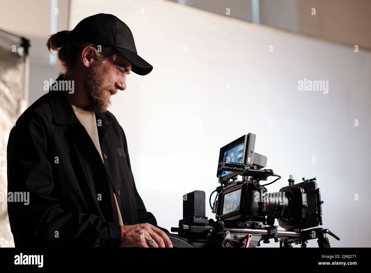 Side view portrait of bearded cameraman watching at screen of steadicam ...
