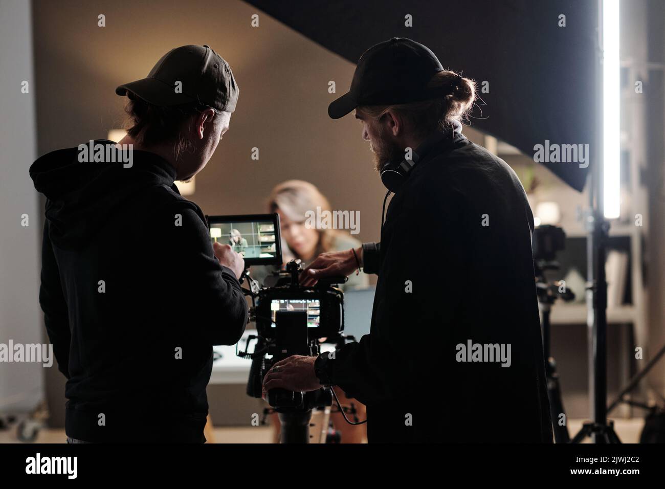 Back view of two young men standing in front of camer aand using ...