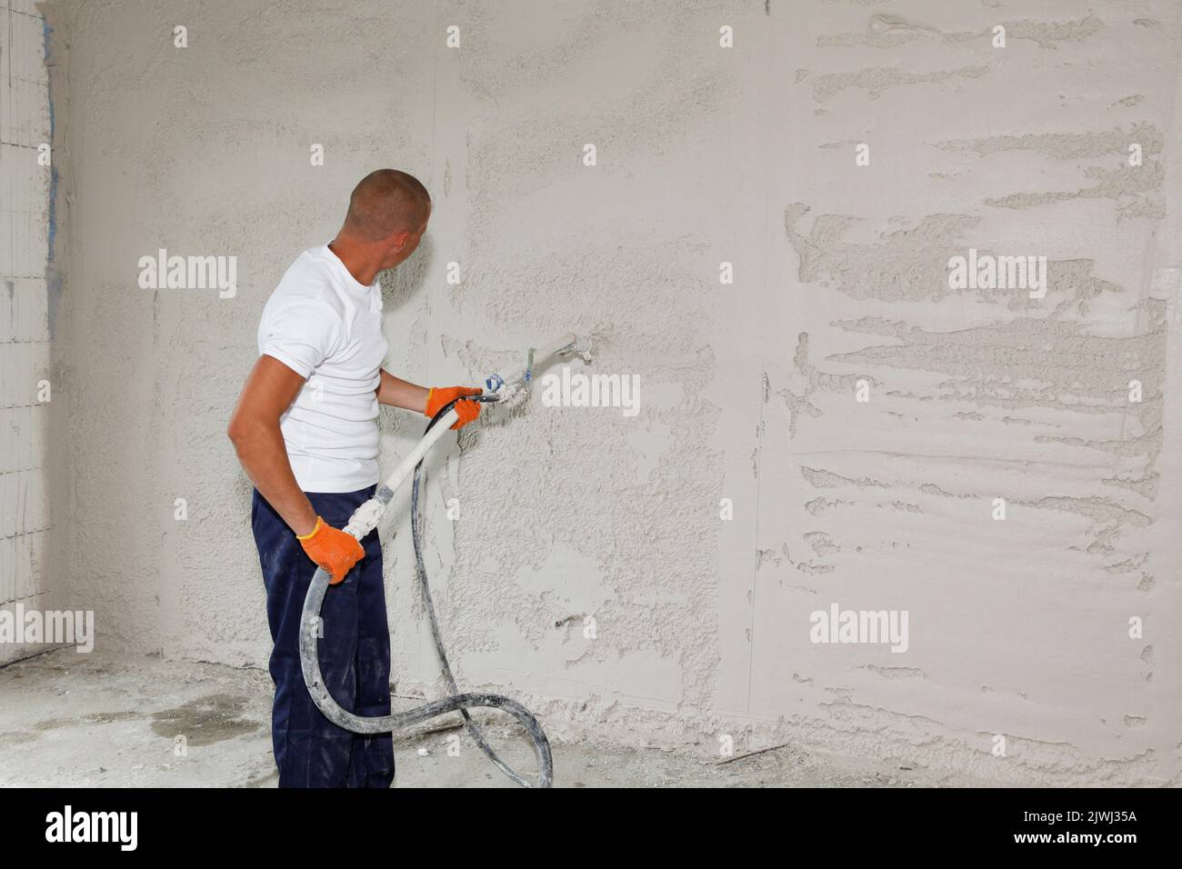 A man is applying stucco on the wall, plastering, coating the wall by ...