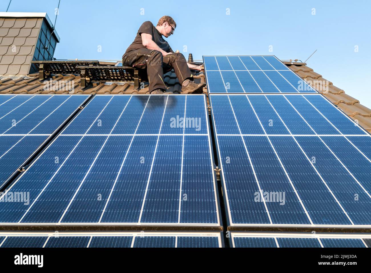 Person next to solar panels on a rooftop Stock Photo - Alamy