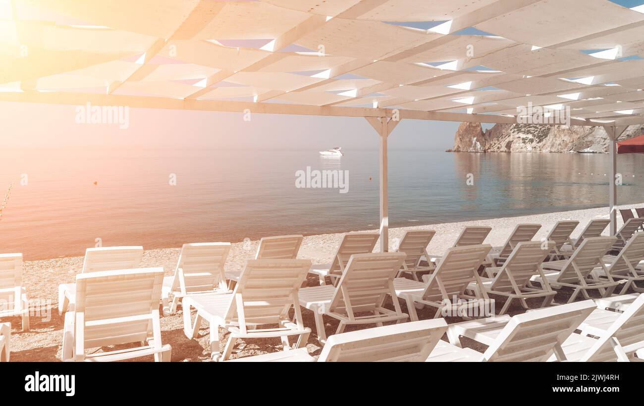 Empty sun loungers under a canopy on the beach. The beach area is empty ...