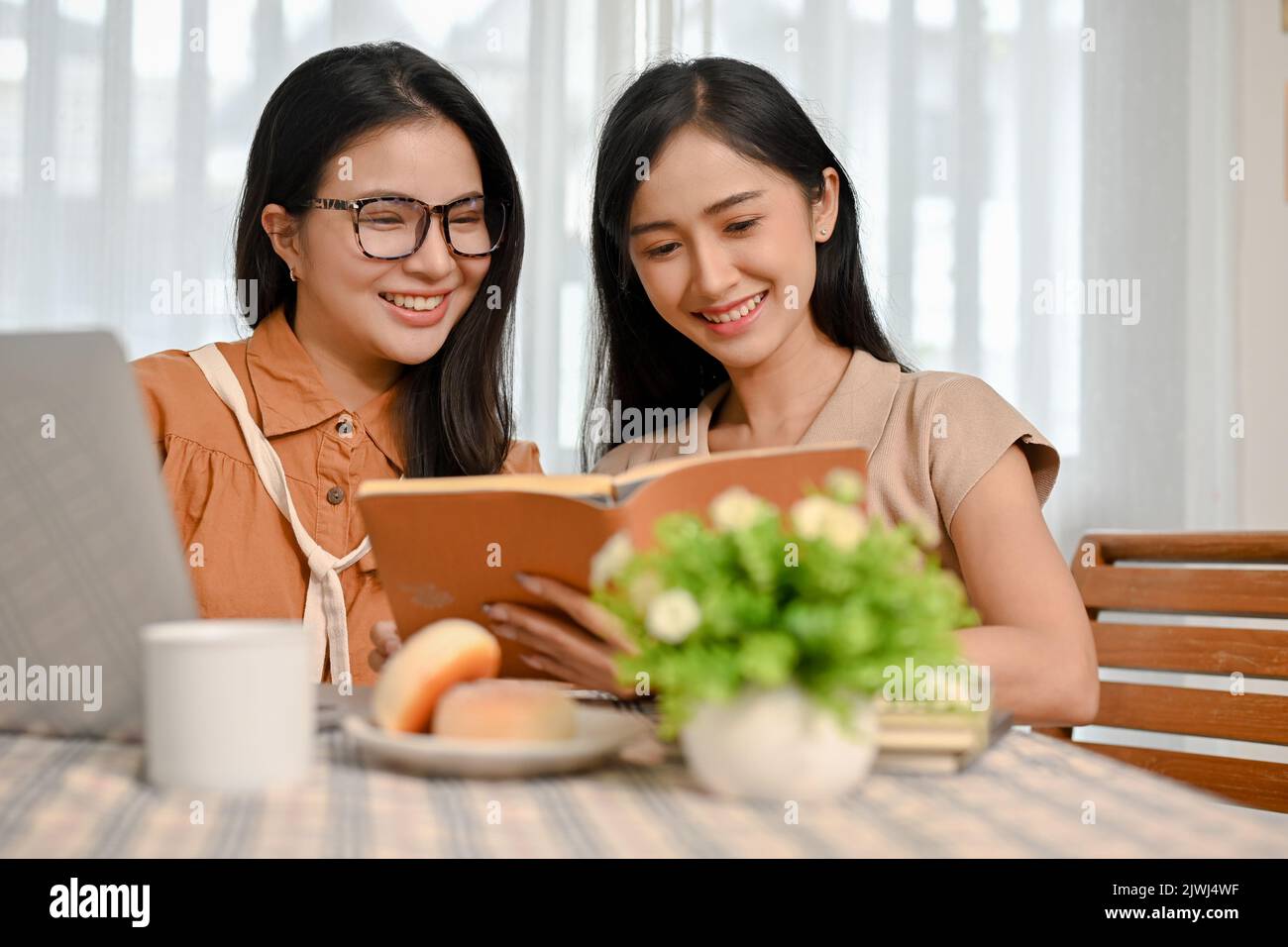 Two beautiful Asian female college students reading a book together ...