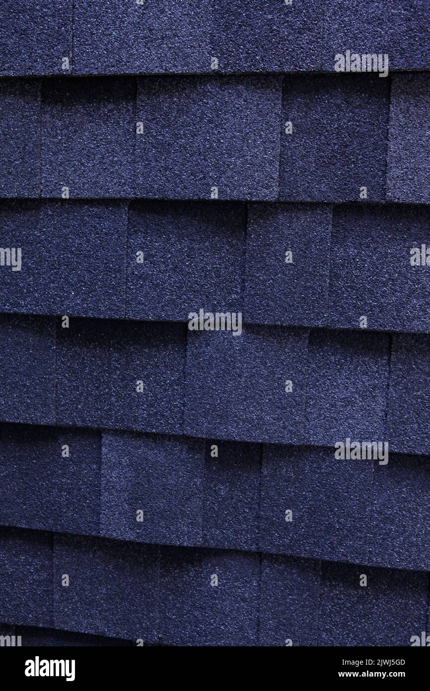 A dark blue architectural asphalt roofing shingles background. A close ...