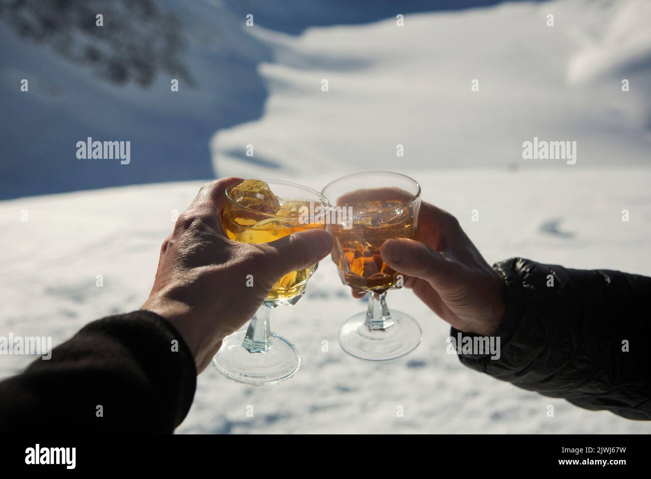 Close up POV hands of friends toasting apres-ski cocktails in snow ...