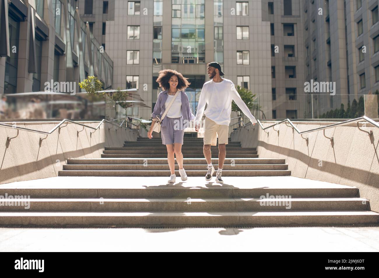Cute couple walking hand in hand and looking happy Stock Photo - Alamy