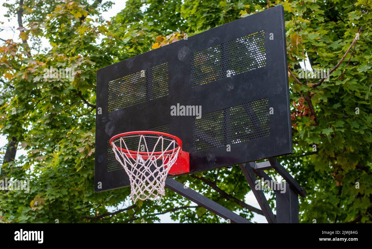 A red hoop on a black metal backboard on a basketball court in a park ...