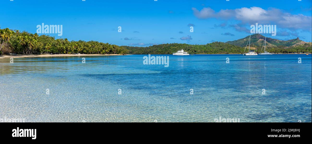 Boats anchored in Blue Lagoon off tropical beach with clear blue water ...