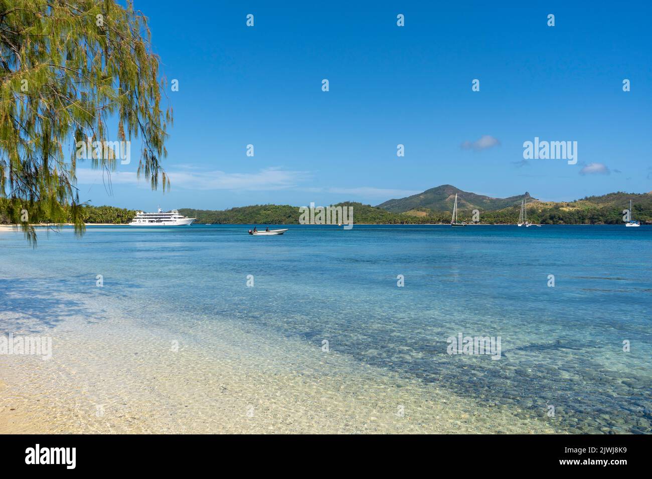 Cruise ship anchored in Blue Lagoon off tropical beach with clear blue ...
