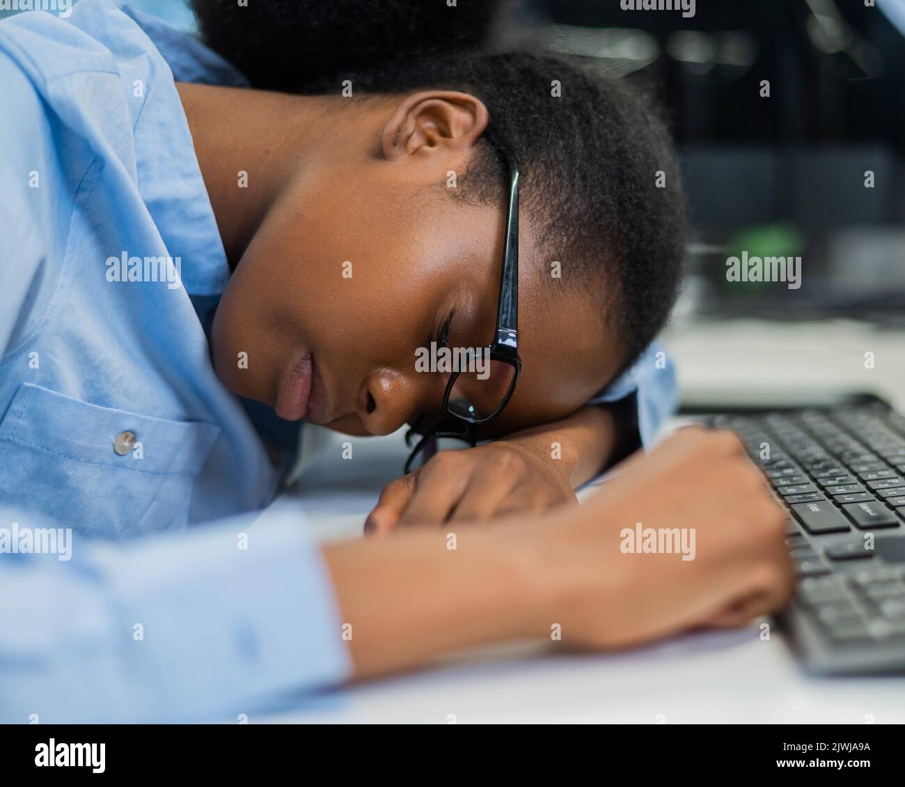 African young woman sleeping at work desk Stock Photo - Alamy