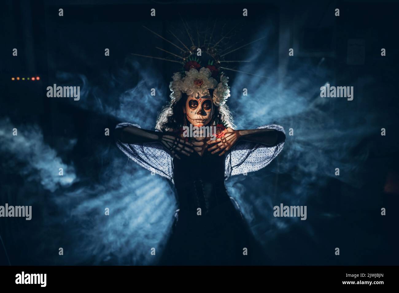 Woman with mexican skull halloween makeup in dark with backlight rays ...