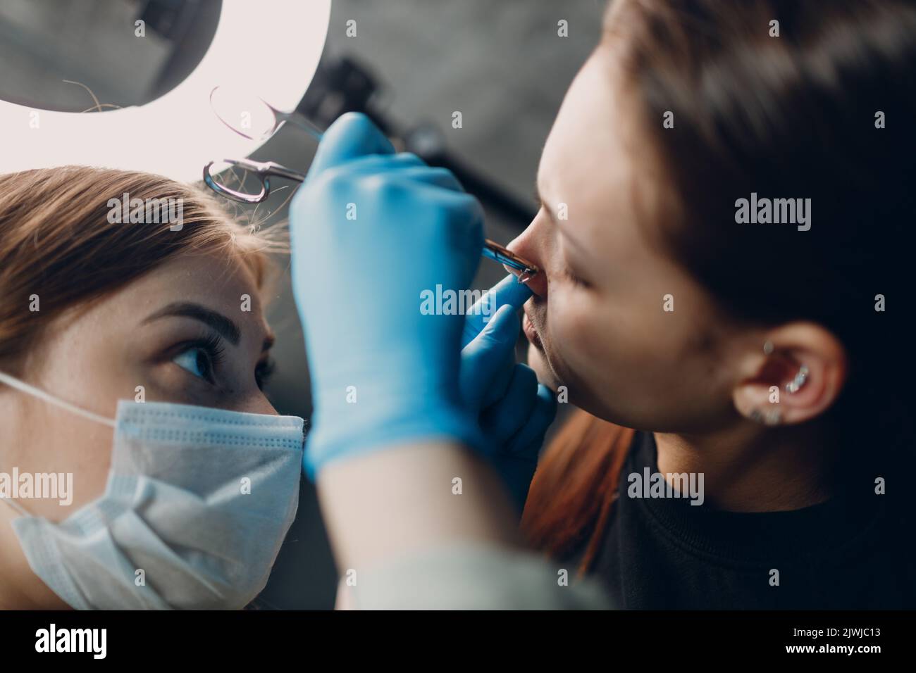Young woman doing piercing nose ring at beauty studio salon Stock Photo ...