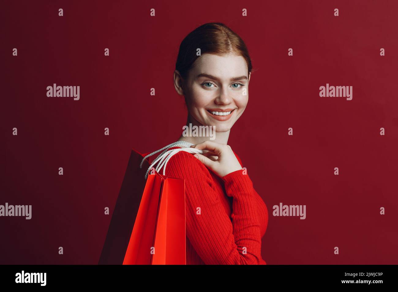 Pretty woman smilng portrait with paper red shopping bags. Black friday ...