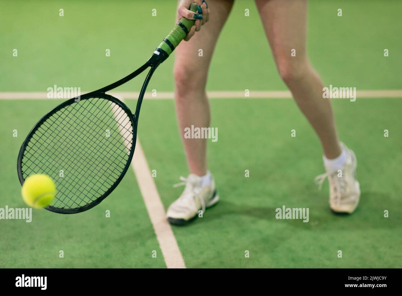 Tennis woman player legs playing training with racket and ball at court ...