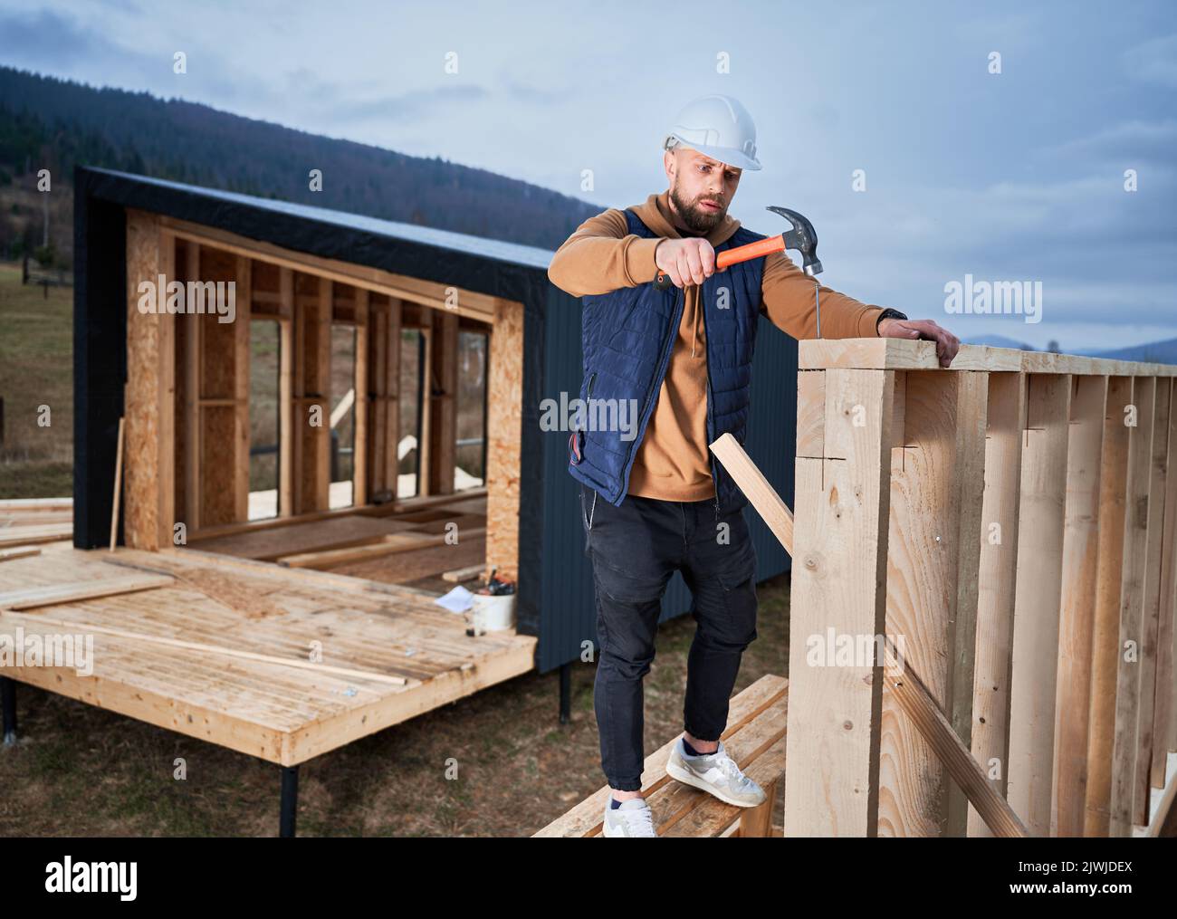 Man worker building wooden frame house on pile foundation. Carpenter ...