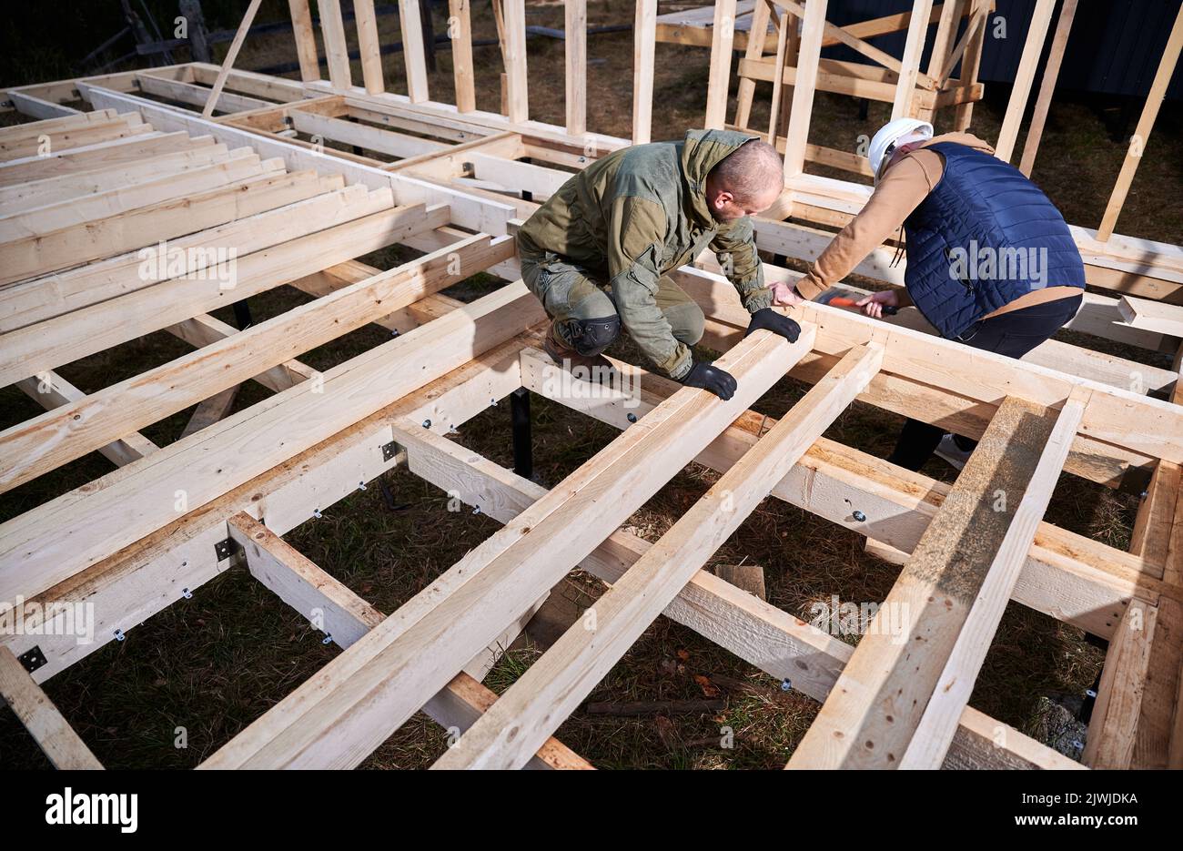 Men workers building wooden frame house on pile foundation. Carpenter ...