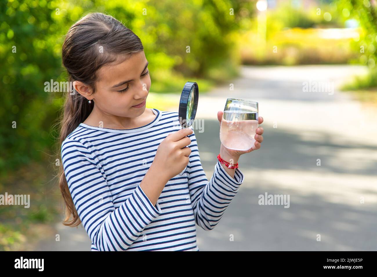 The child examines the water with a magnifying glass. Selective focus ...