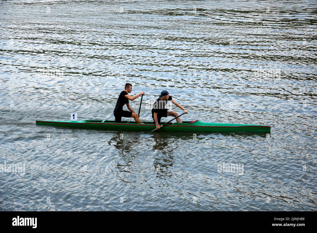 Two young man athletes are sailing canoe on river, controlling oars ...