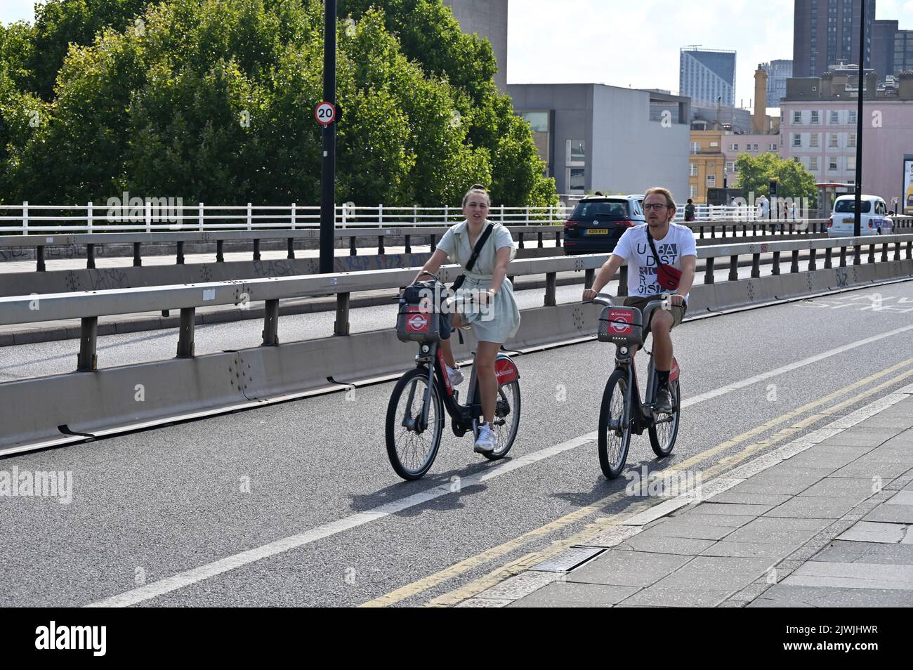 A man and a woman cycle across Waterloo Bridge, London on Santander ...