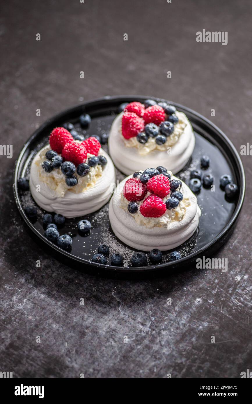 Mini Pavlova cakes topped with berries and mascarpone cheese Stock ...