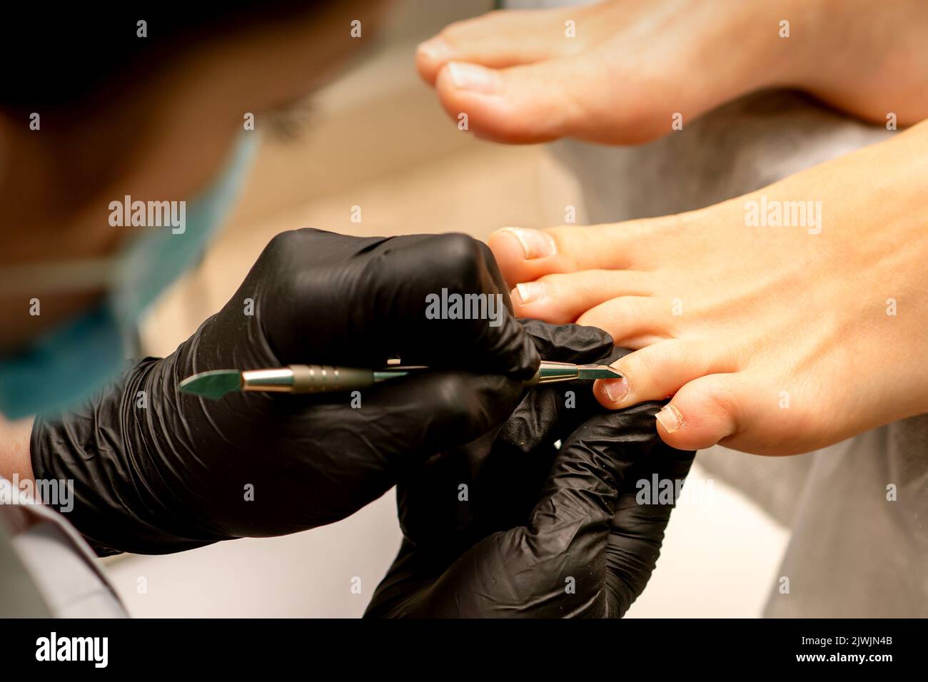 Professional pedicure. Process of cuticle removal on female toes in spa ...