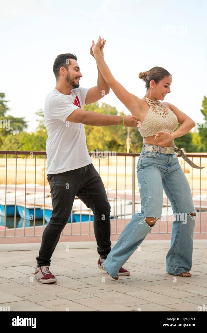 Vertical photo of two happy friends dancing next to an urban lake Stock ...