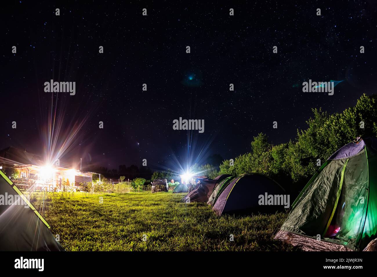 Night camping under starry sky. Glowing tourist tent, under beautiful evening sky full of stars ...