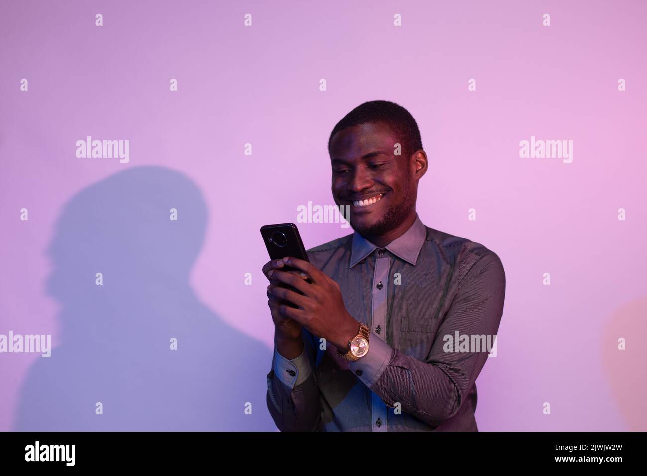 african man using his phone smiling Stock Photo - Alamy